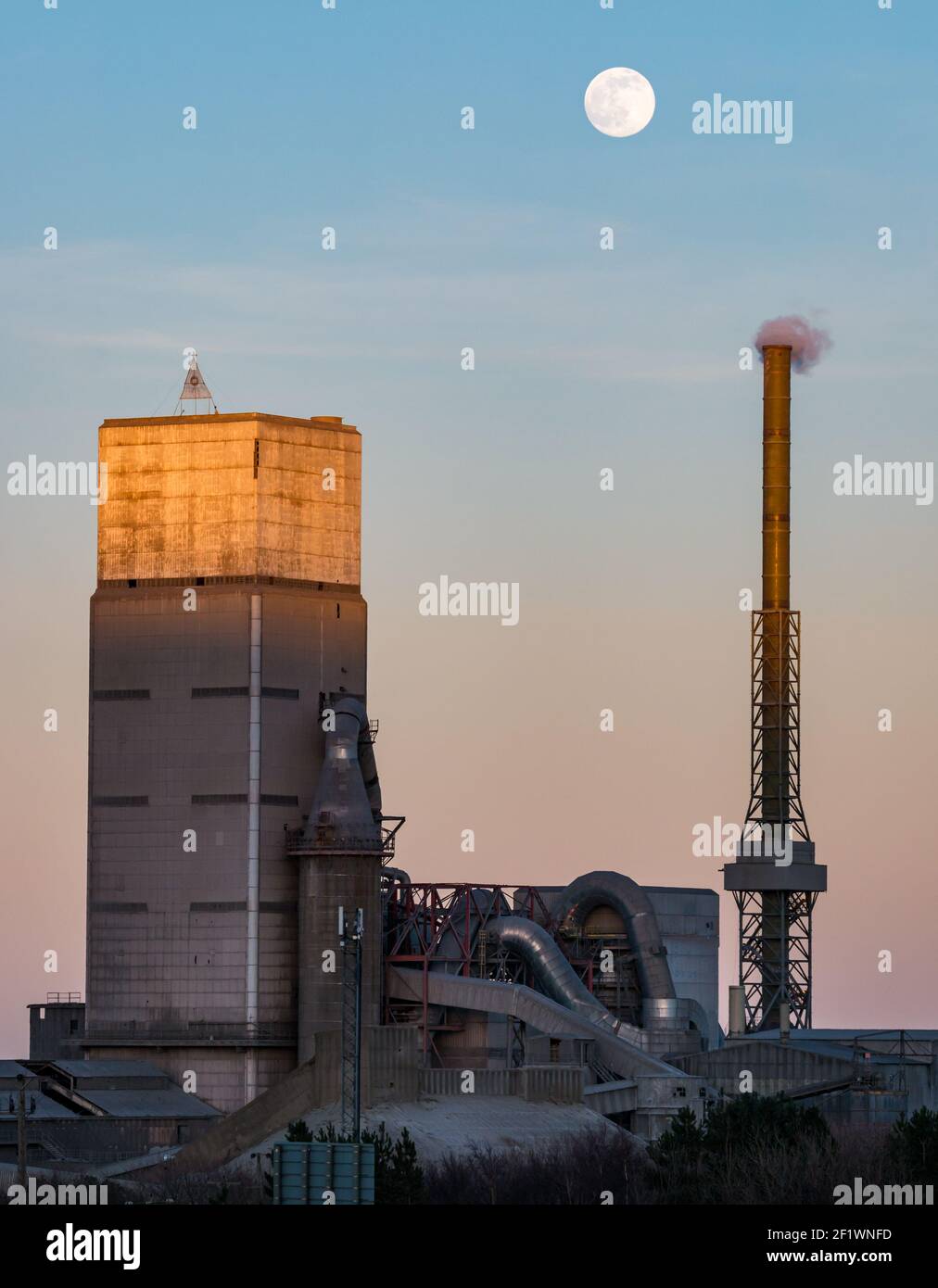 Full snow moon rising over industrial tower at sunset, Dunbar cement ...