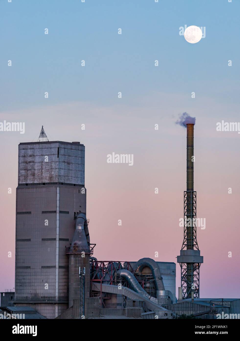 Full snow moon rising over industrial tower at sunset, Dunbar cement ...