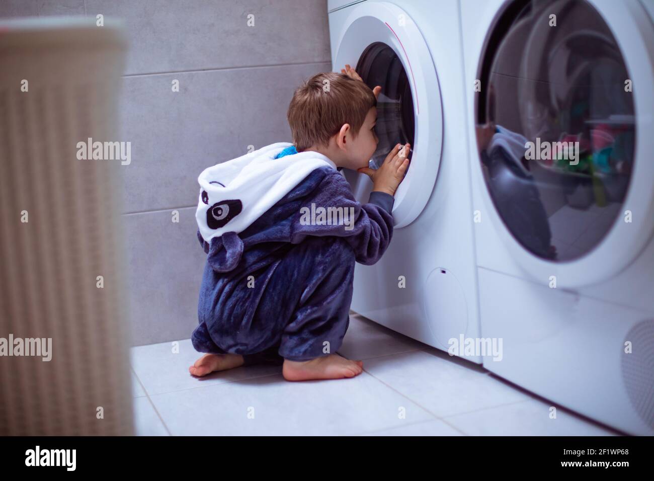 the toddler is looking into the washing machine while wash Stock Photo ...