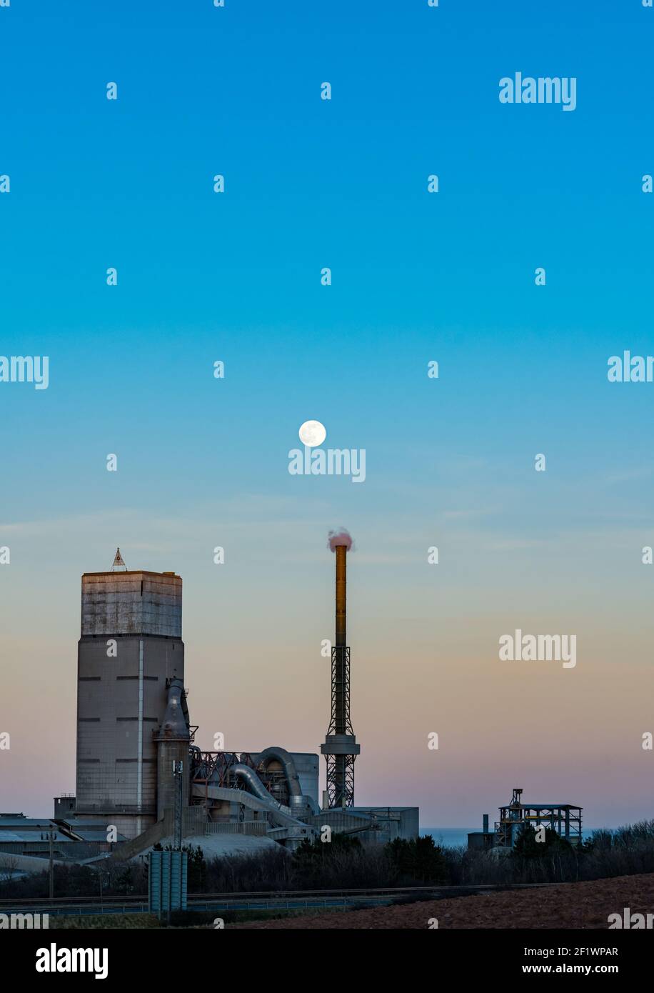 Full snow moon rising over industrial tower at sunset, Dunbar cement ...
