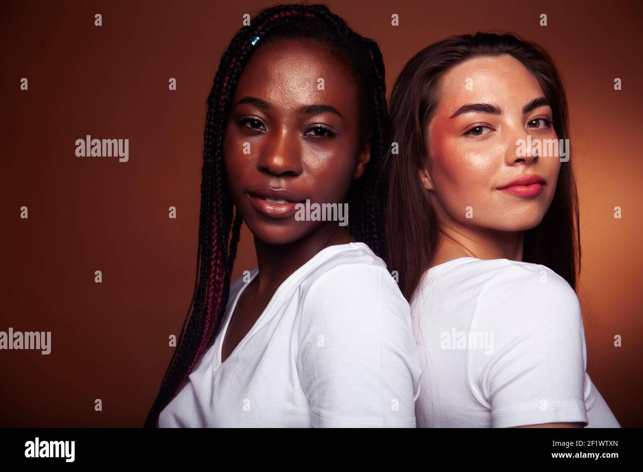 young pretty asian, afro woman posing cheerful together on brown ...