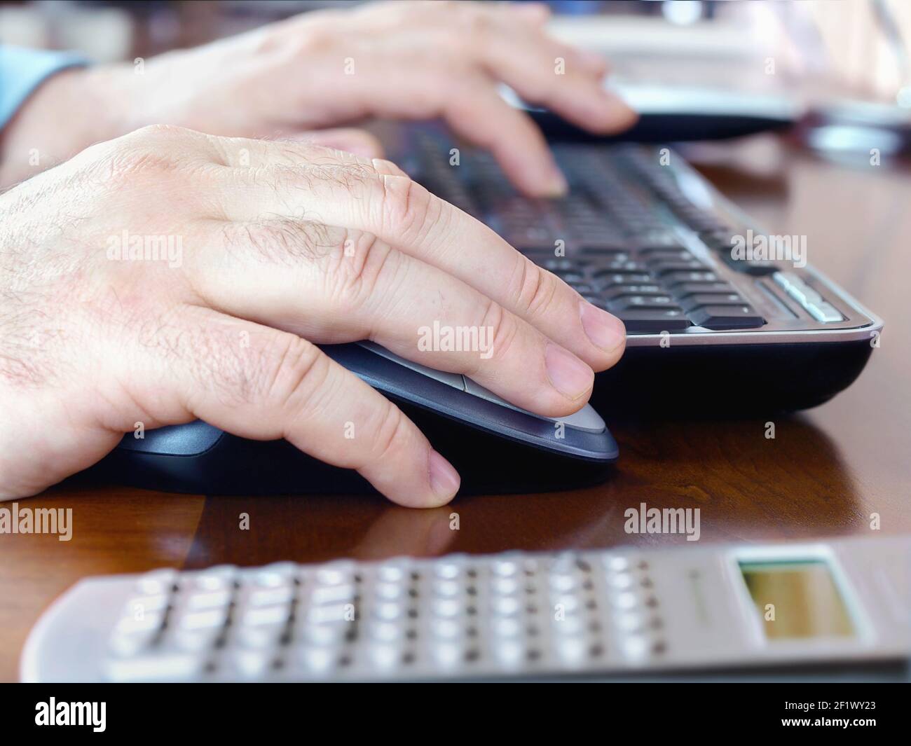 Man's hands on computer mouse and keyboard Stock Photo - Alamy