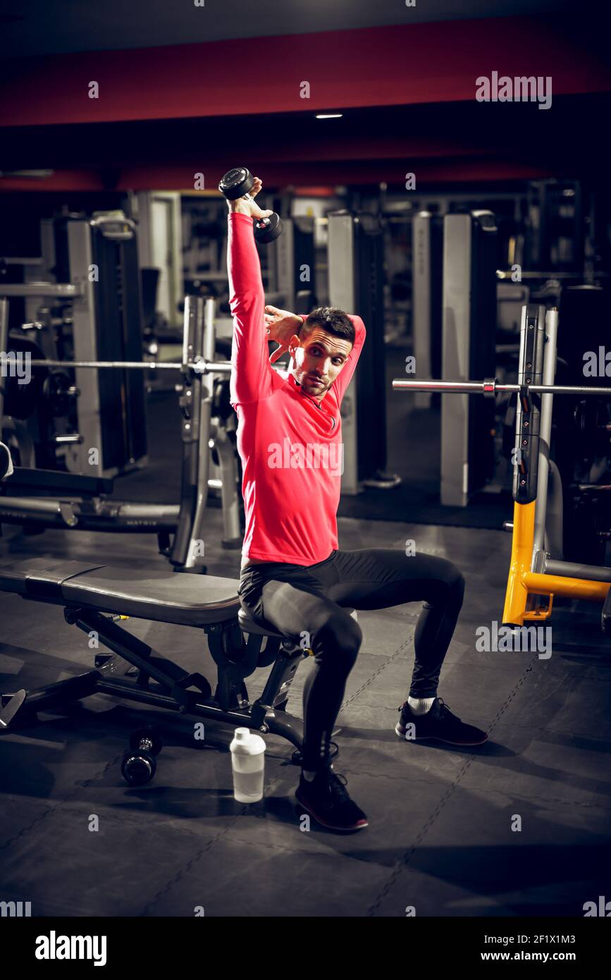 Inspiring young shape man doing exercise for triceps while sitting on ...