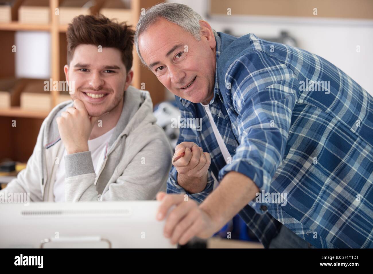mature worker smiling with young apprentice Stock Photo - Alamy