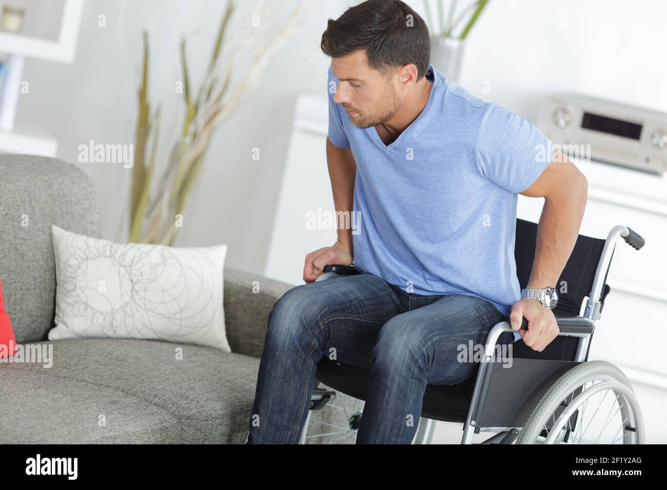 handicapped man moving himself from the wheelchair to couch Stock Photo ...
