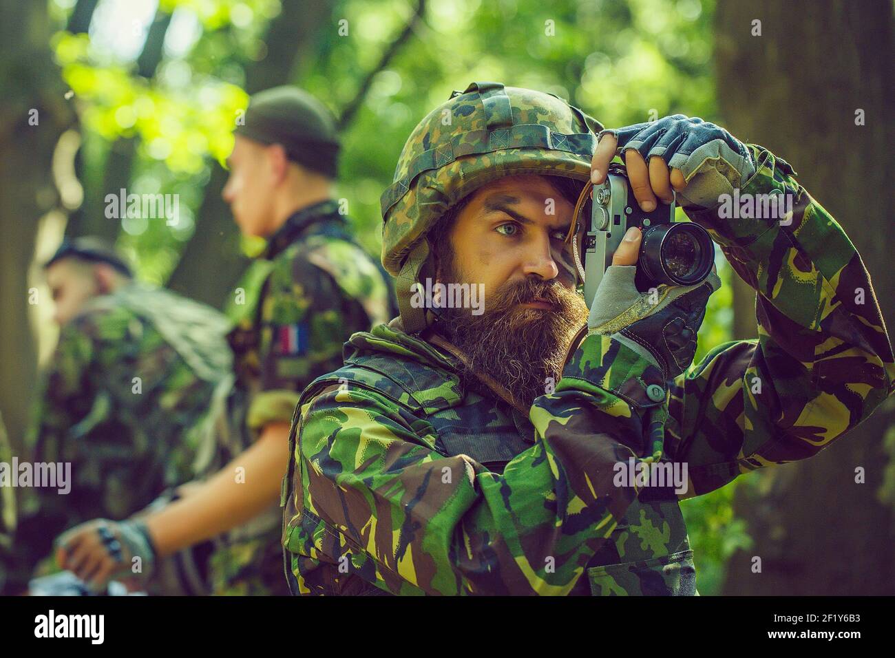 Soldier man reporter with serious face in ammunition and helmet holding ...
