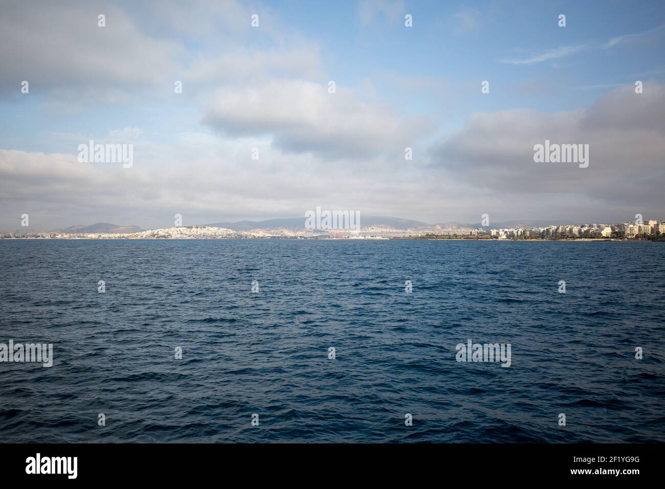 A scenic view of a partly rough sea near a village under a cloudy sky ...