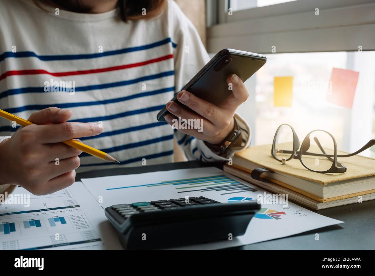 Close up of accountant hand holding smartphone while working on ...