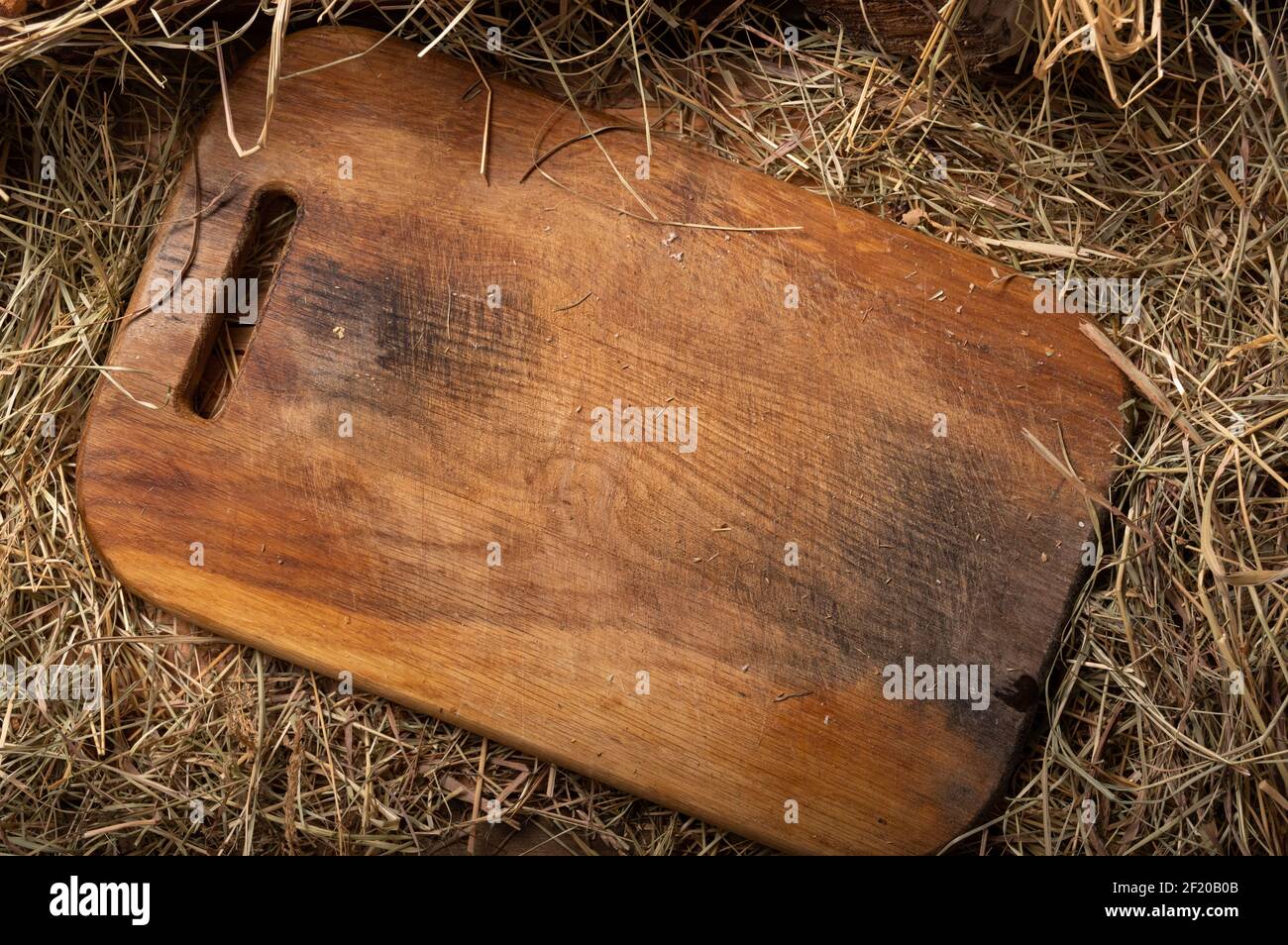 Empty board for cutting food. Board lying on the hay. Background from ...