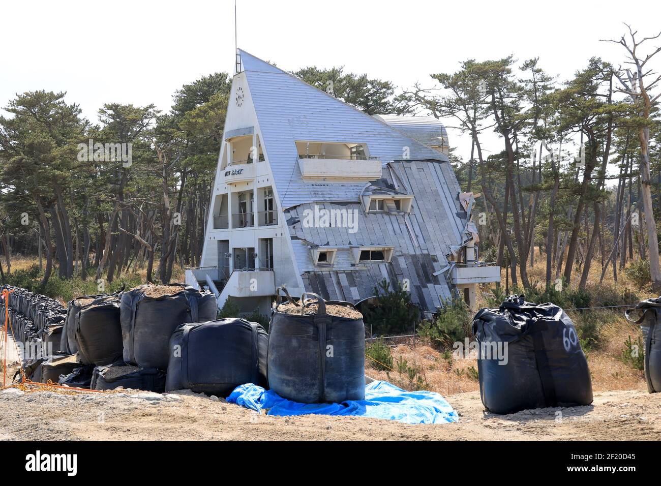 Futaba, Japan. 10th Mar, 2021. A wrecked house stands behind sandbags ...