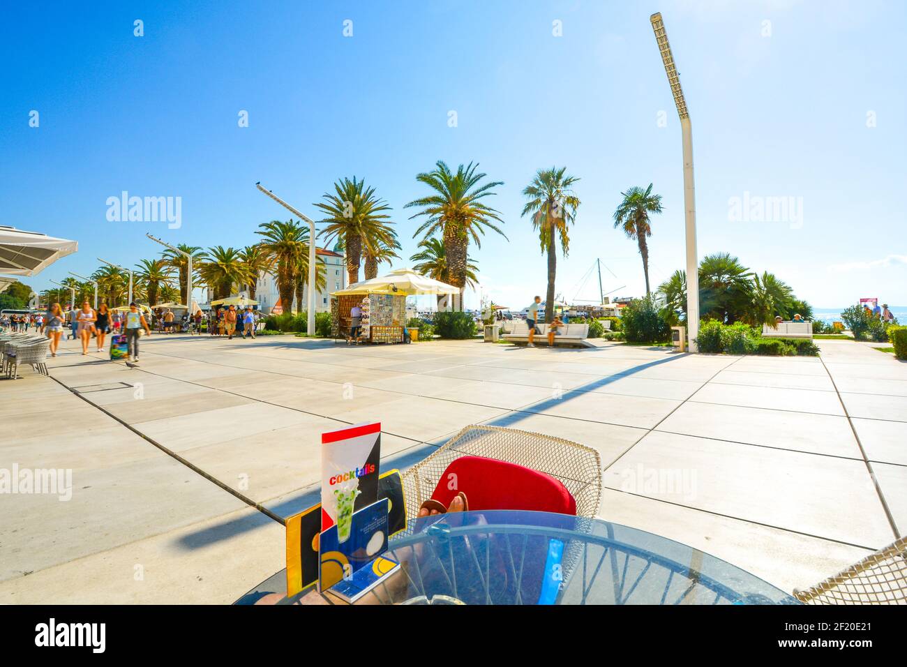 A tourist relaxes with their feet up at a sidewalk waterfront cafe on ...