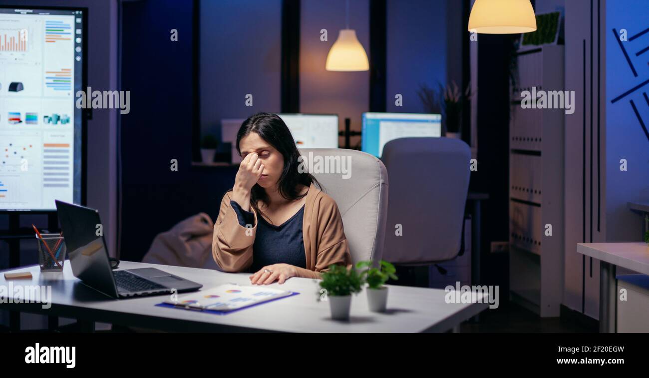 Portrait of of stressed at work doing overtime to complete important ...