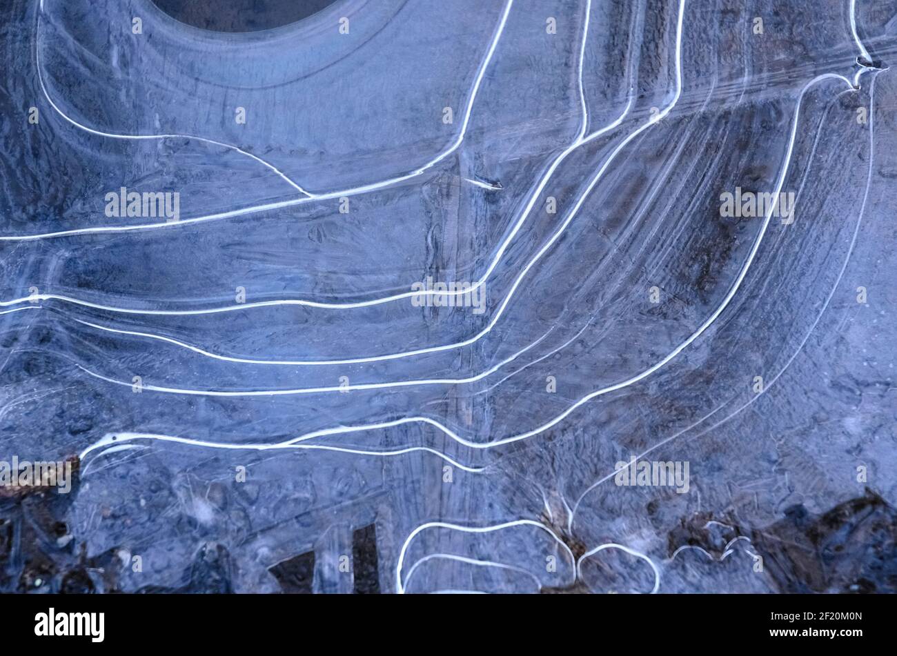 Frozen water in a puddle on the ground with abstract structures and ...