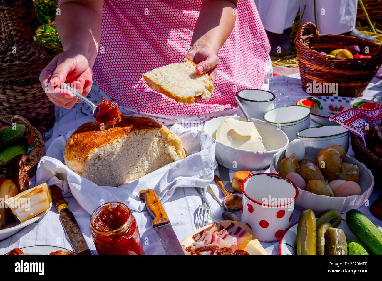 Traditional meal, woman smears jam on bread, breakfast in open at the ...