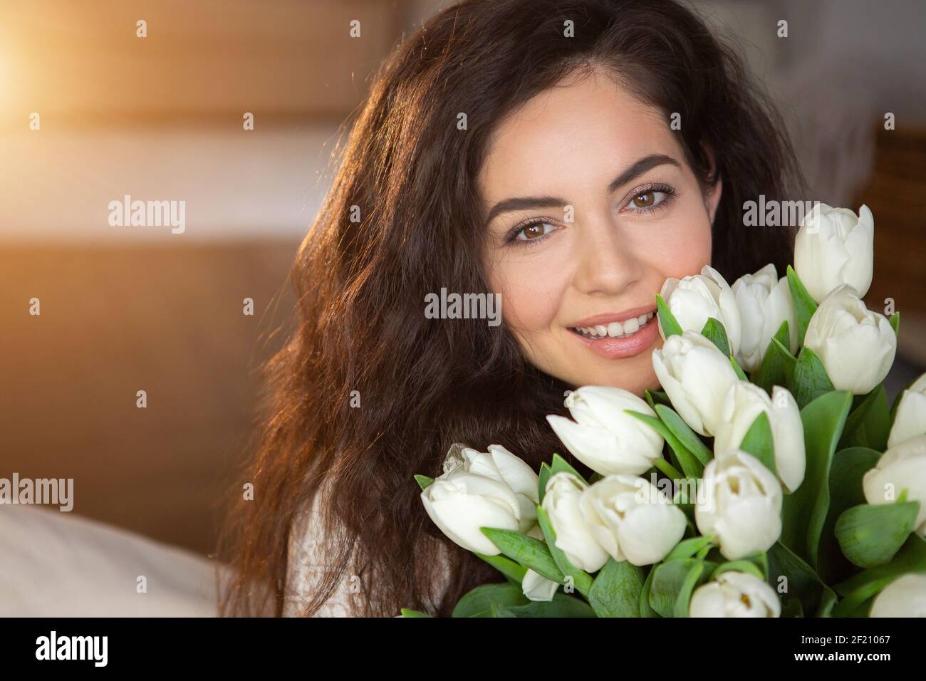 Closeup portrait of a beautiful young woman holding big bunch of white ...