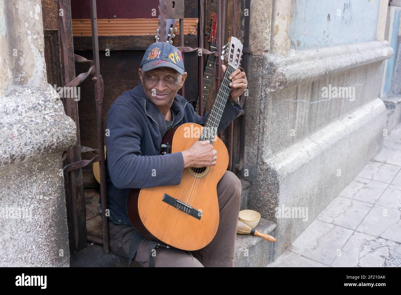 Cuba, Havana - Man playing guitar on his stoop, surrounded by musical ...