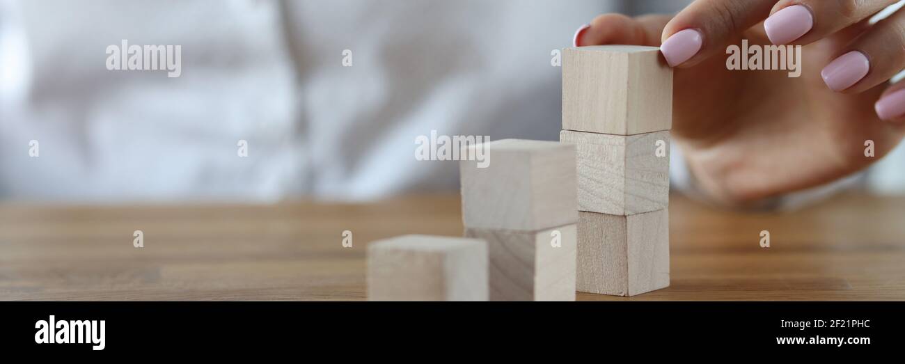 Female hand builds tower from wooden blocks Stock Photo - Alamy