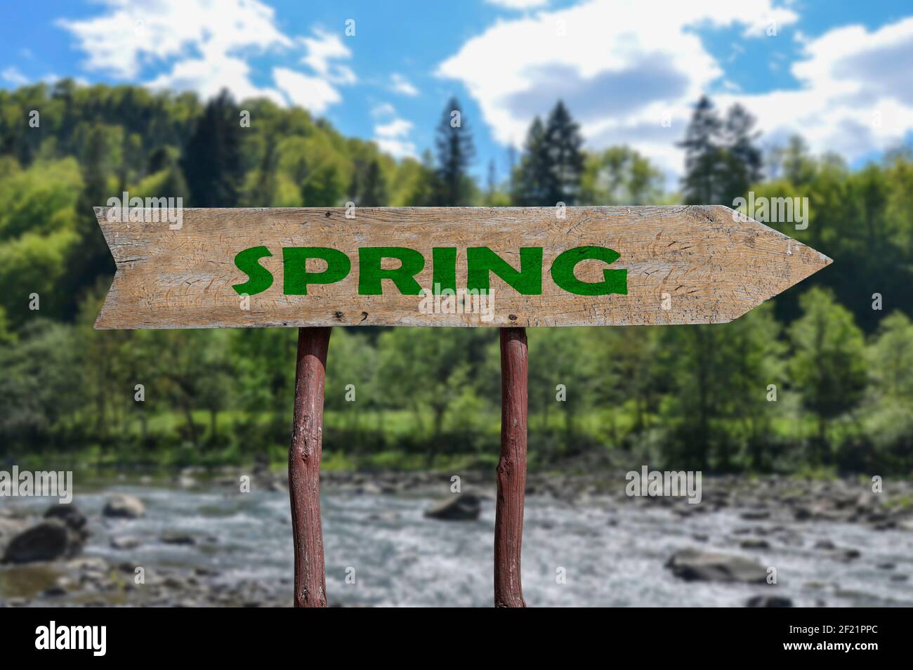 Spring wooden arrow road sign against river and forest background ...