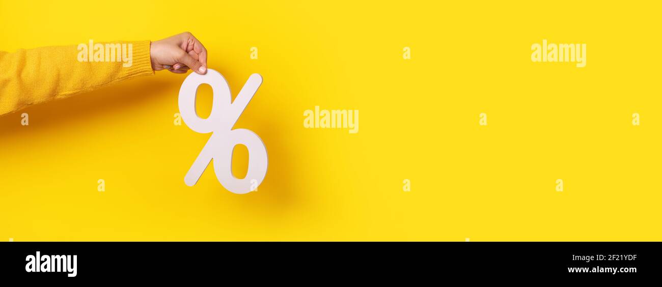 Woman hand holding 3D white percentage sign over yellow background ...