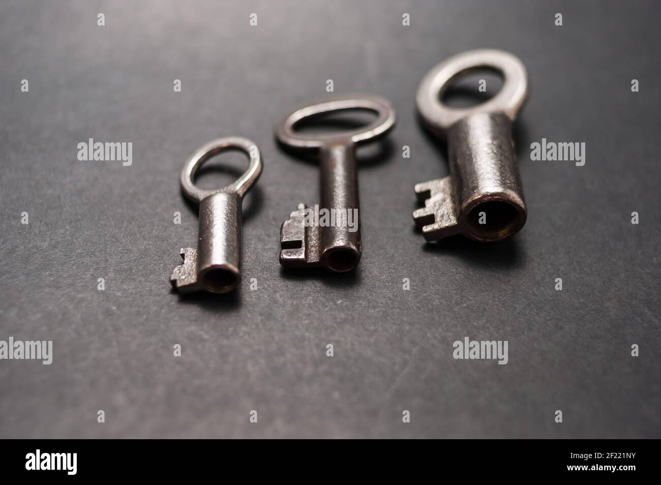 Group of three very small old beard keys on a black background. View at ...