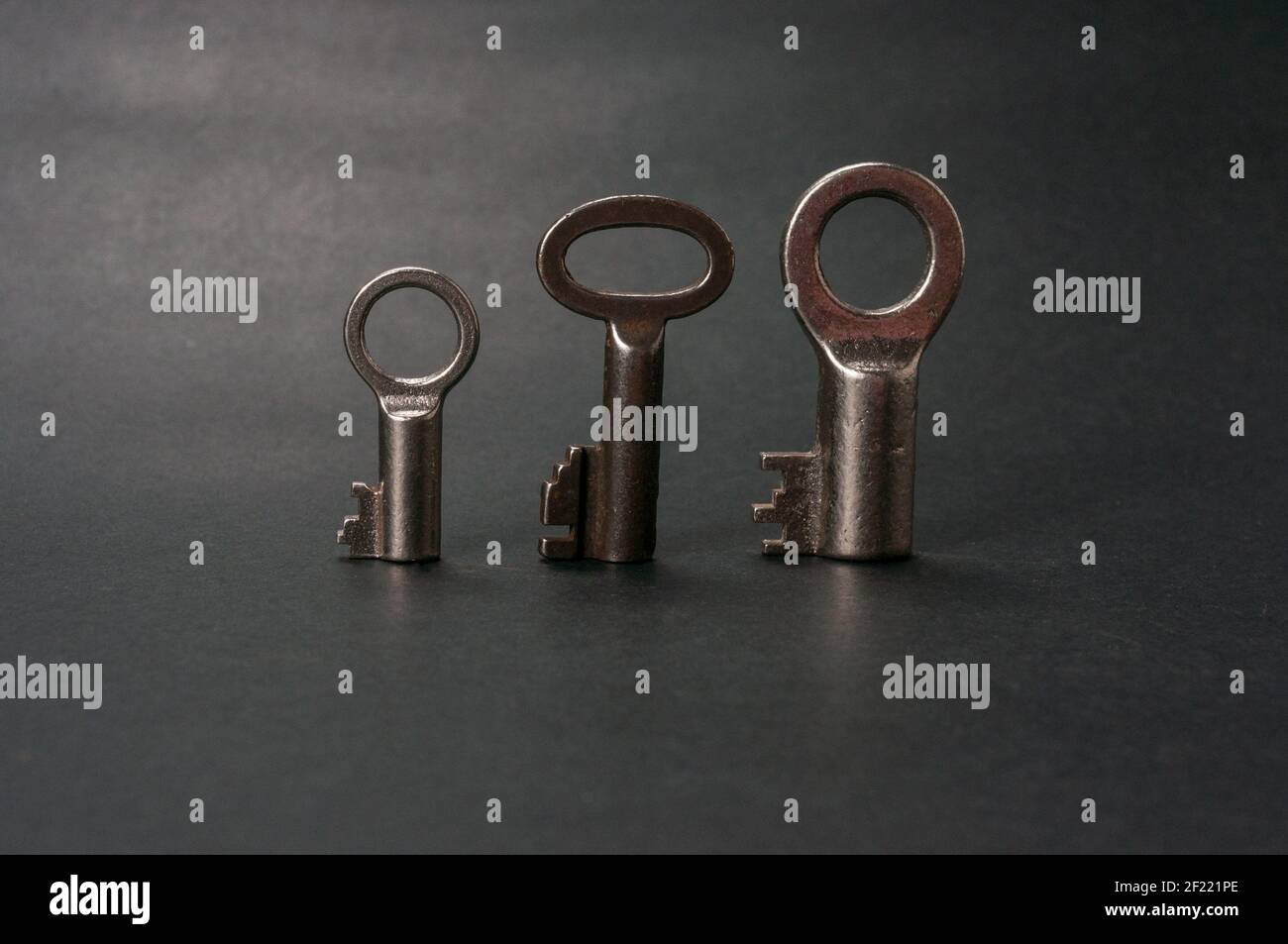 Group of three very small old beard keys on a black background. View at ...