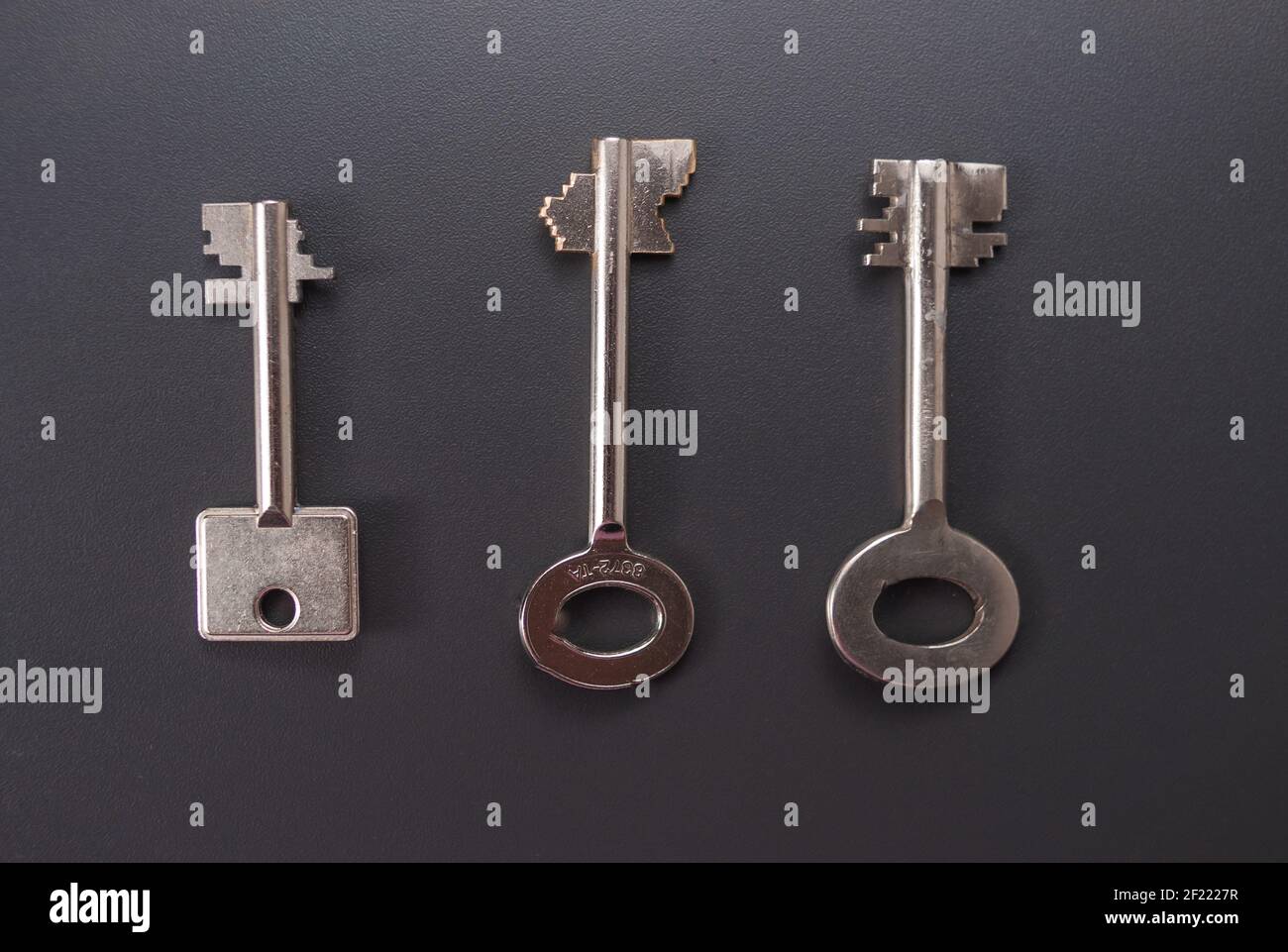 Still life with three safes keys in different designs on a black ...