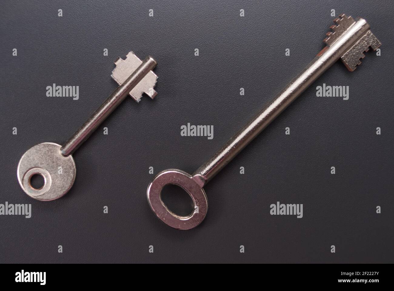 One small and one full-size safe key, safe keys on a dark background ...