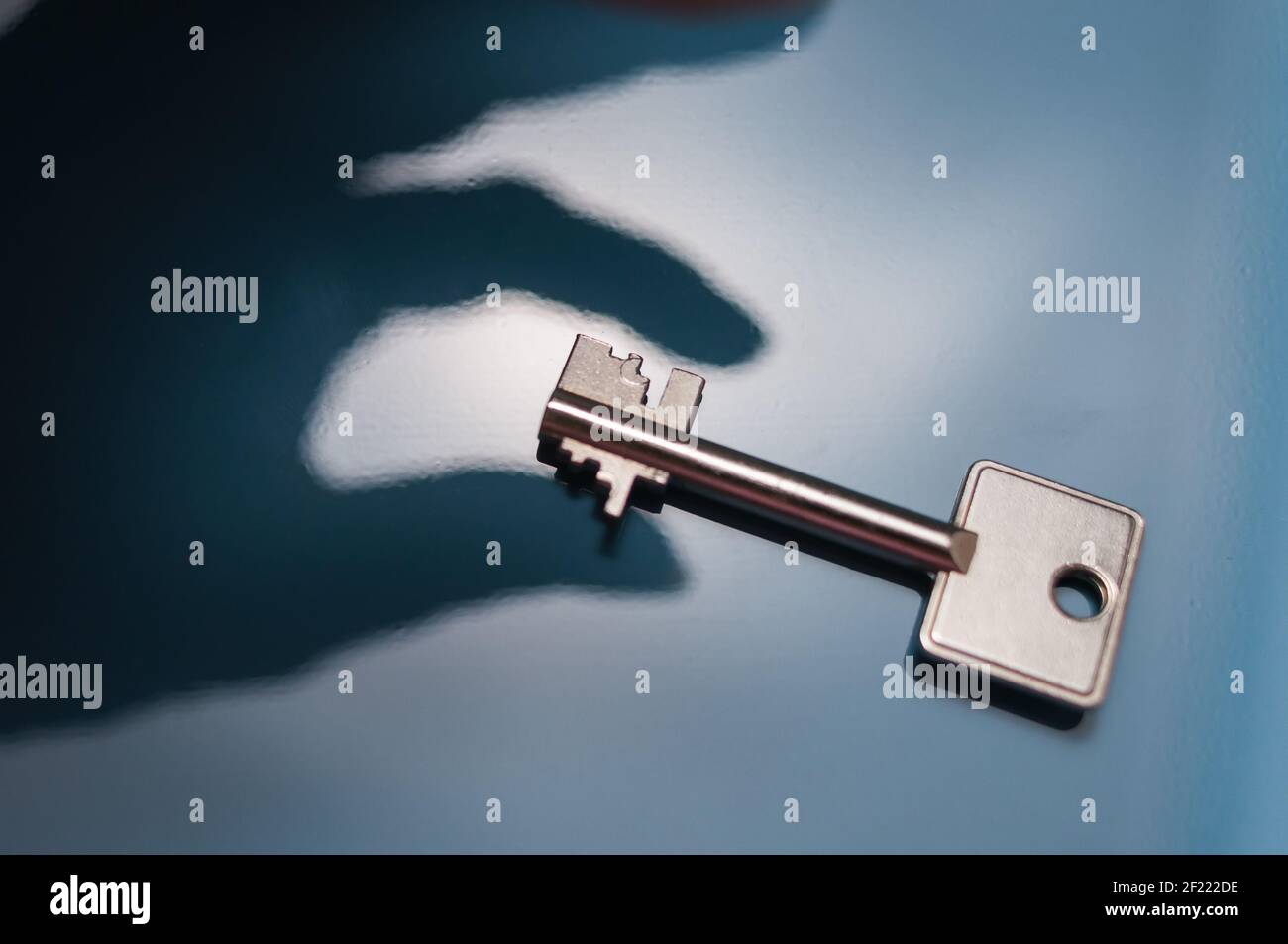 Shadow play safe key is gripped by a shadow hand in front of a bluish ...