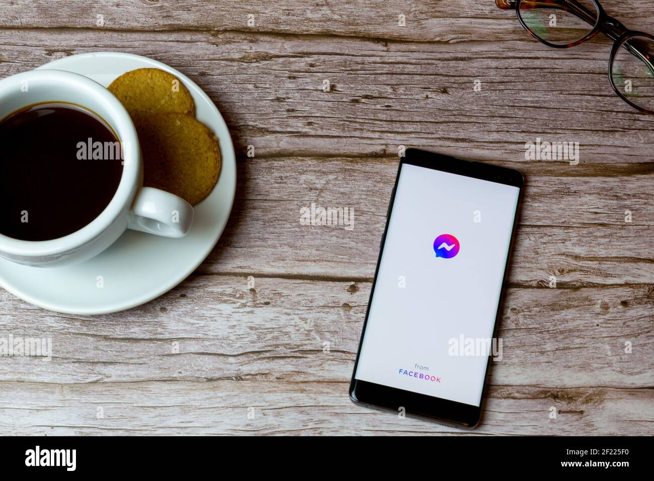 A Mobile phone or cell phone laid on a wooden table with the Facebook ...