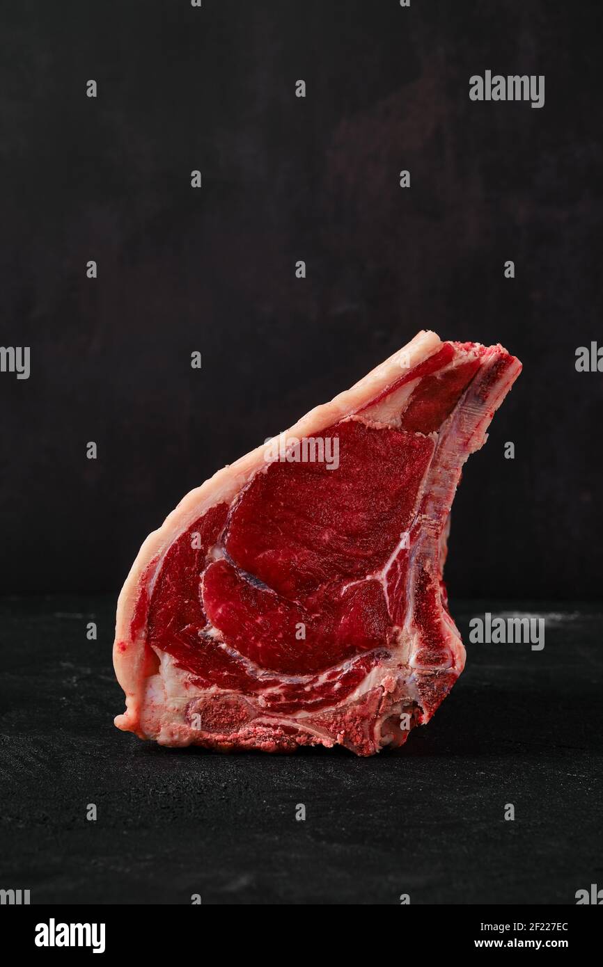 Raw rib-eye steak bone in on dark background closeup Stock Photo - Alamy
