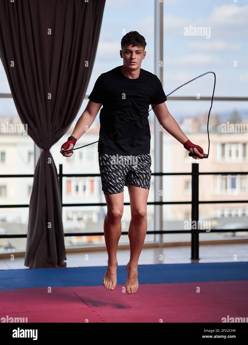 Young kickbox fighter jumping rope warming up for training in the gym ...