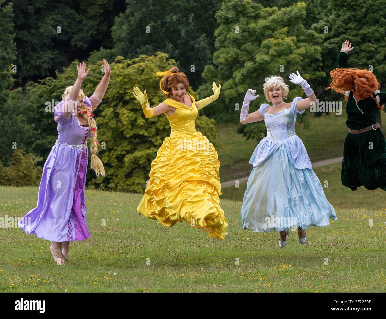 Four Disney princesses at a charity event jump in the air and wave ...