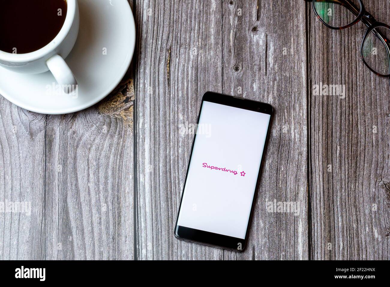 A mobile phone or cell phone laid on a wooden table with the superdrug ...