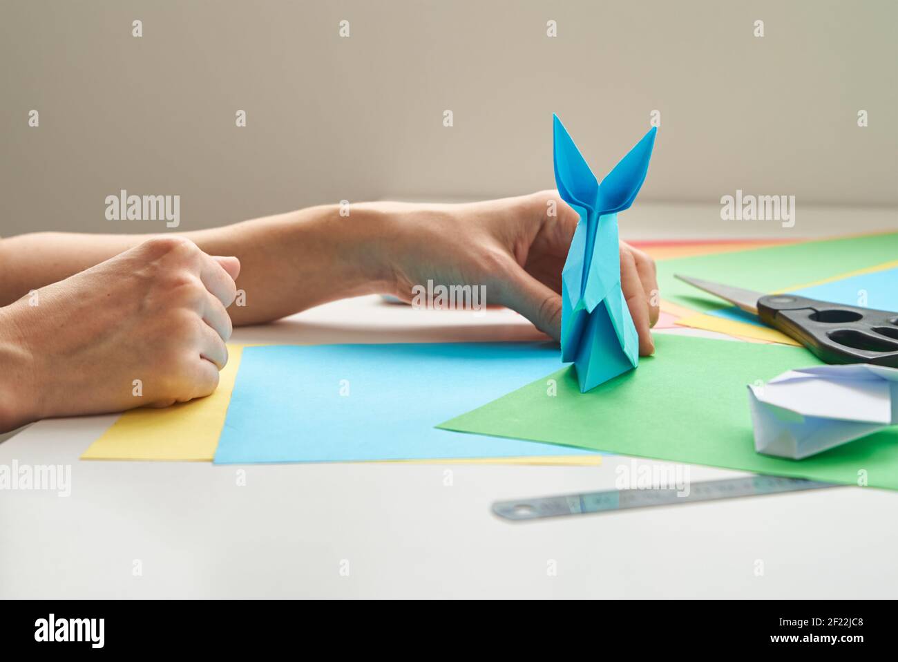 DIY concept. Woman make origami easter rabbit from color paper. Origami ...