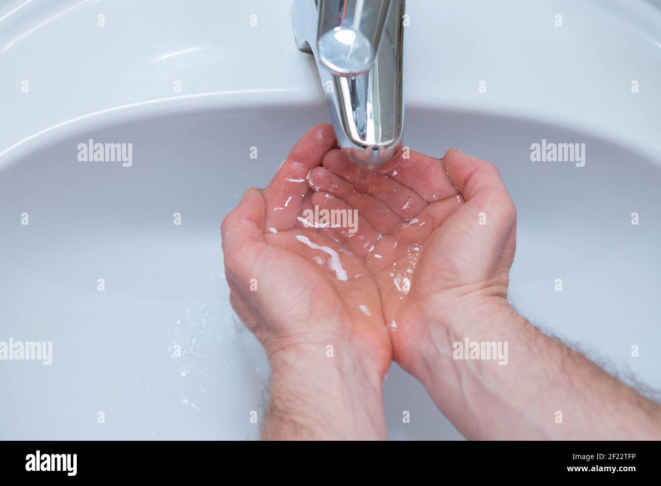 A Man is washing his hands under flowing tap water flow on sink in ...