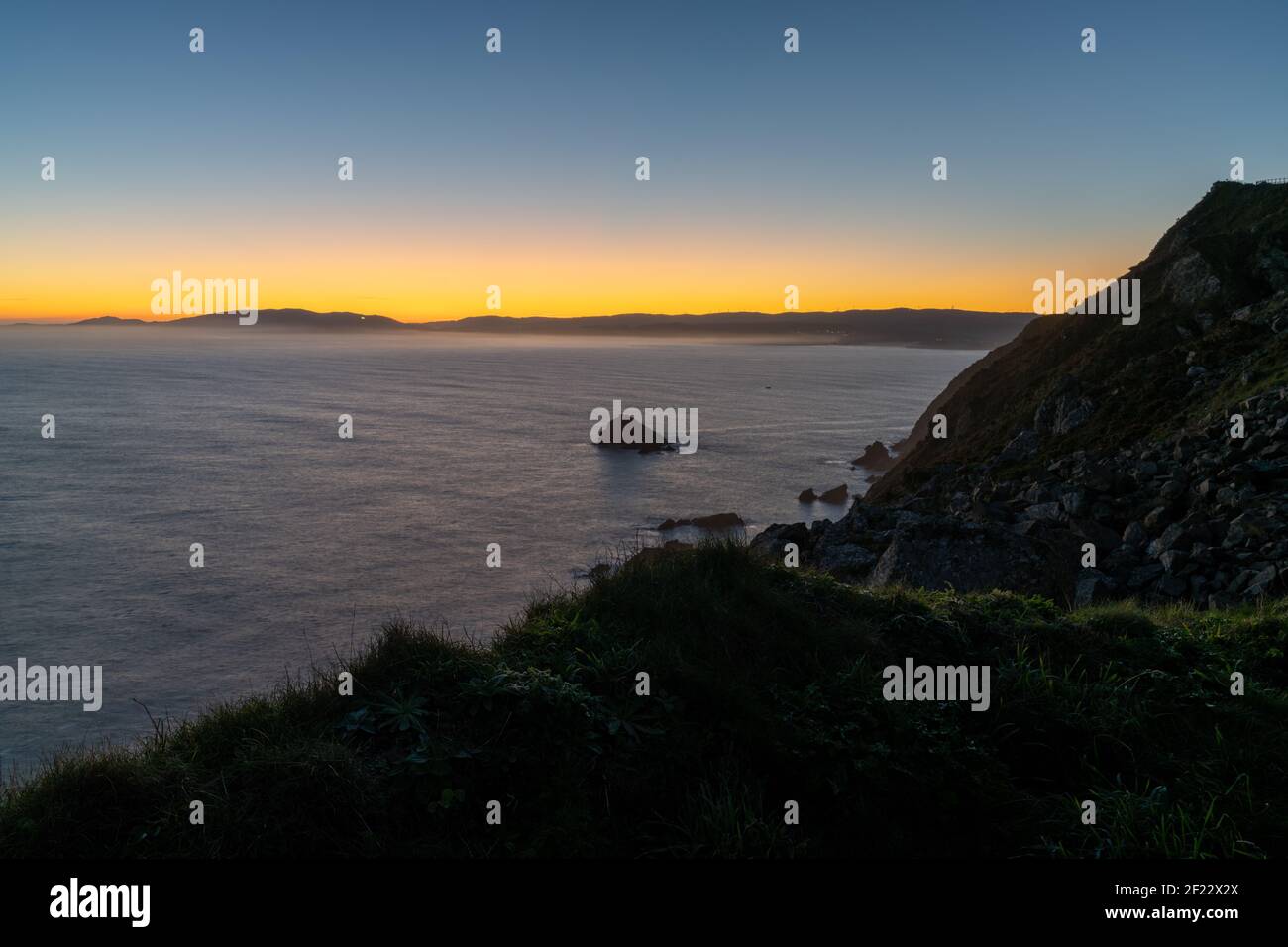 Gorgeous sunrise over the ocean with mountains and cliffs in silhouette ...