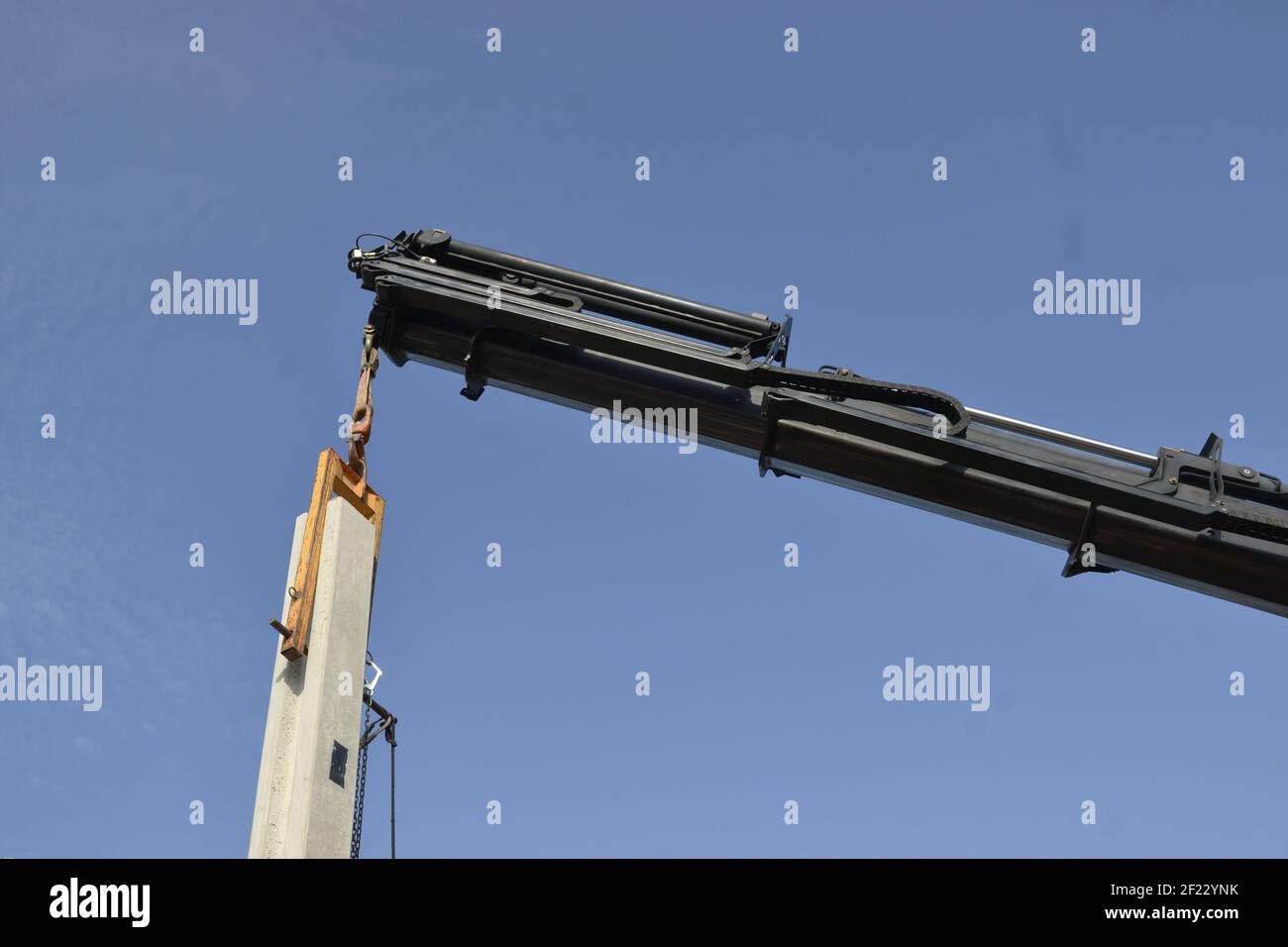 Crane. Crane lifting column for fixation with blue sky background ...