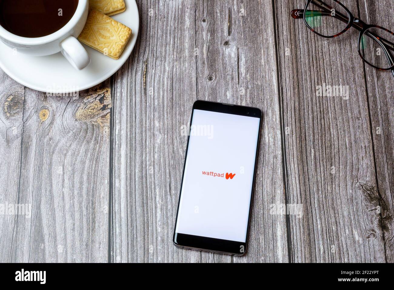 A mobile phone or cell phone on a wooden table with the Wattpad app ...