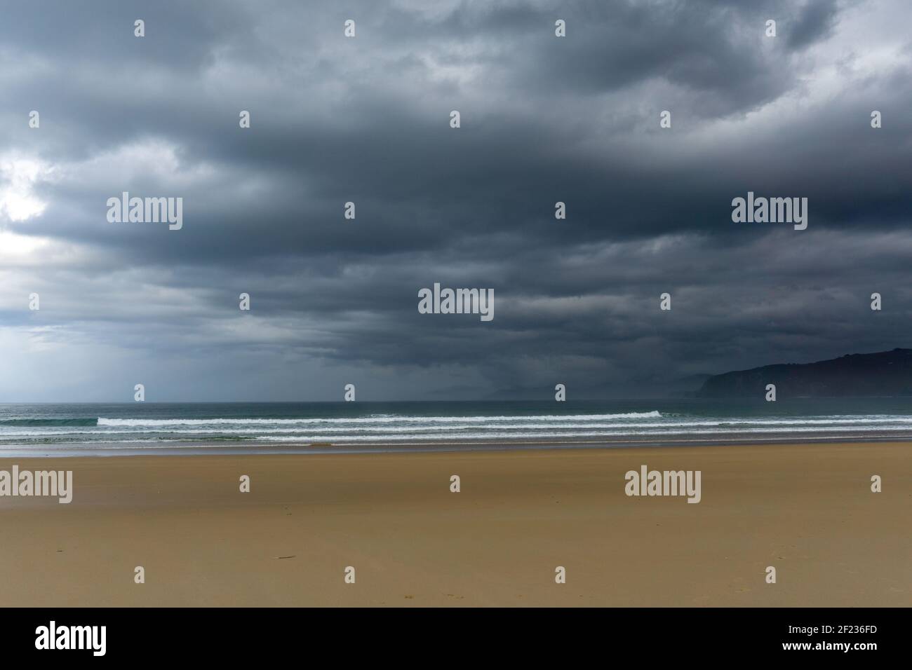 Empty and large beautiful golden sand beach underneath a bad weather ...