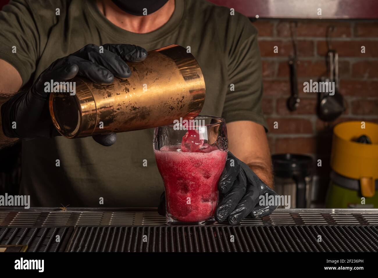 Barman in the bar pouring red alcohol cocktail in a glass. Summer party ...