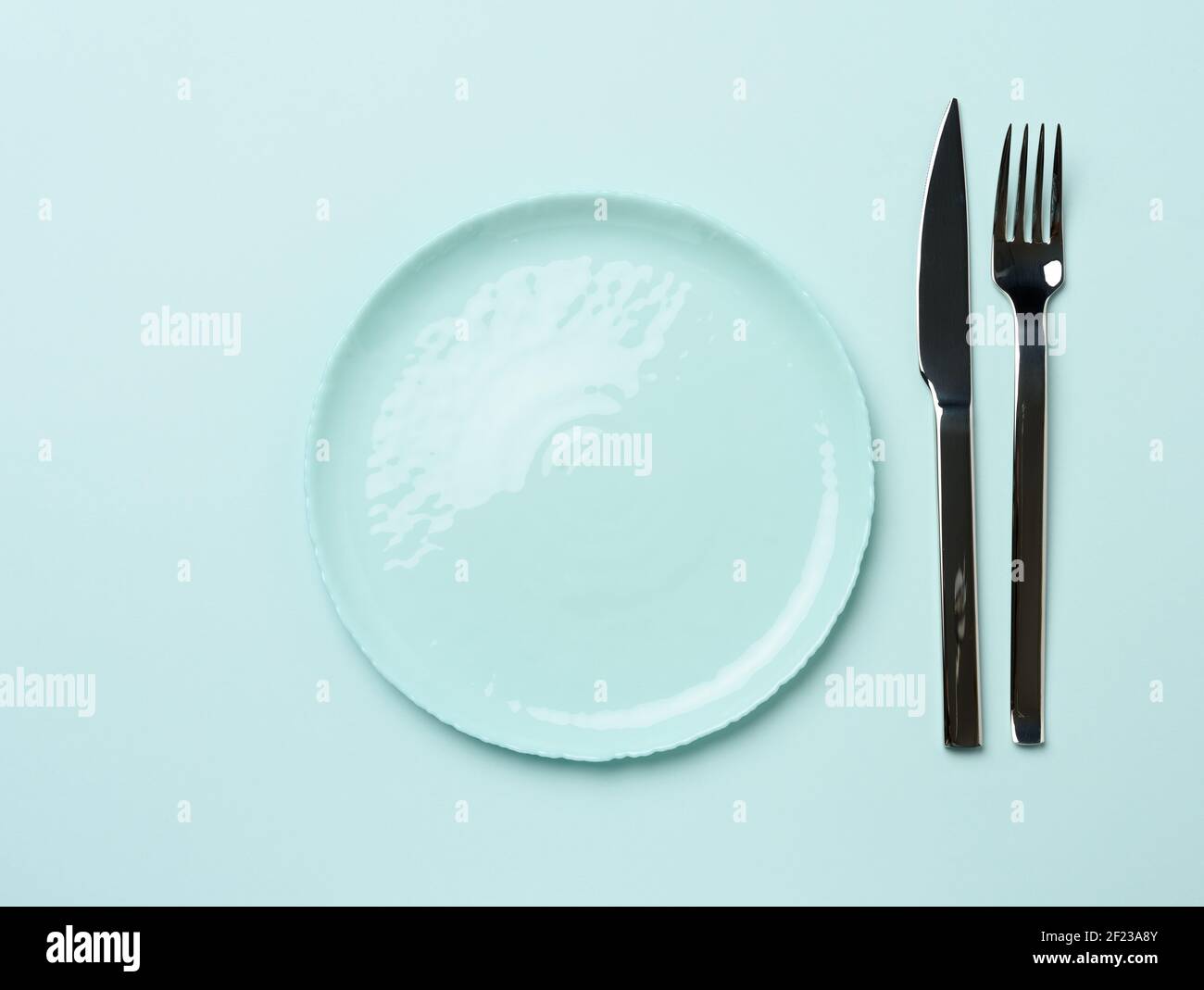 Round ceramic plates, fork with knife on a green background, top view ...
