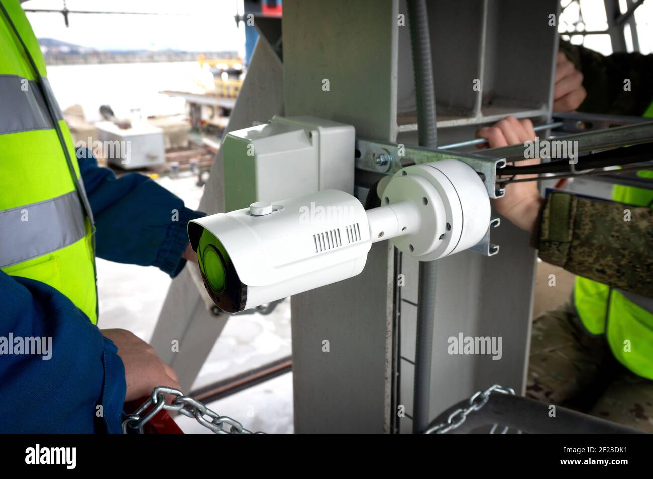 a specialist installs a street surveillance camera on a metal structure ...
