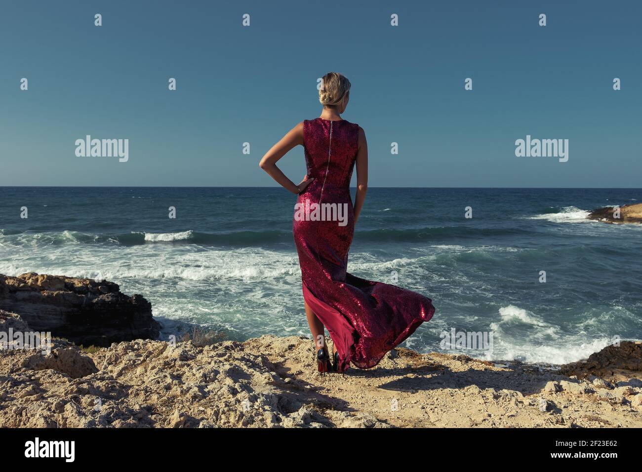 Gorgeous fashion model in elegant red dress posing on sea background ...