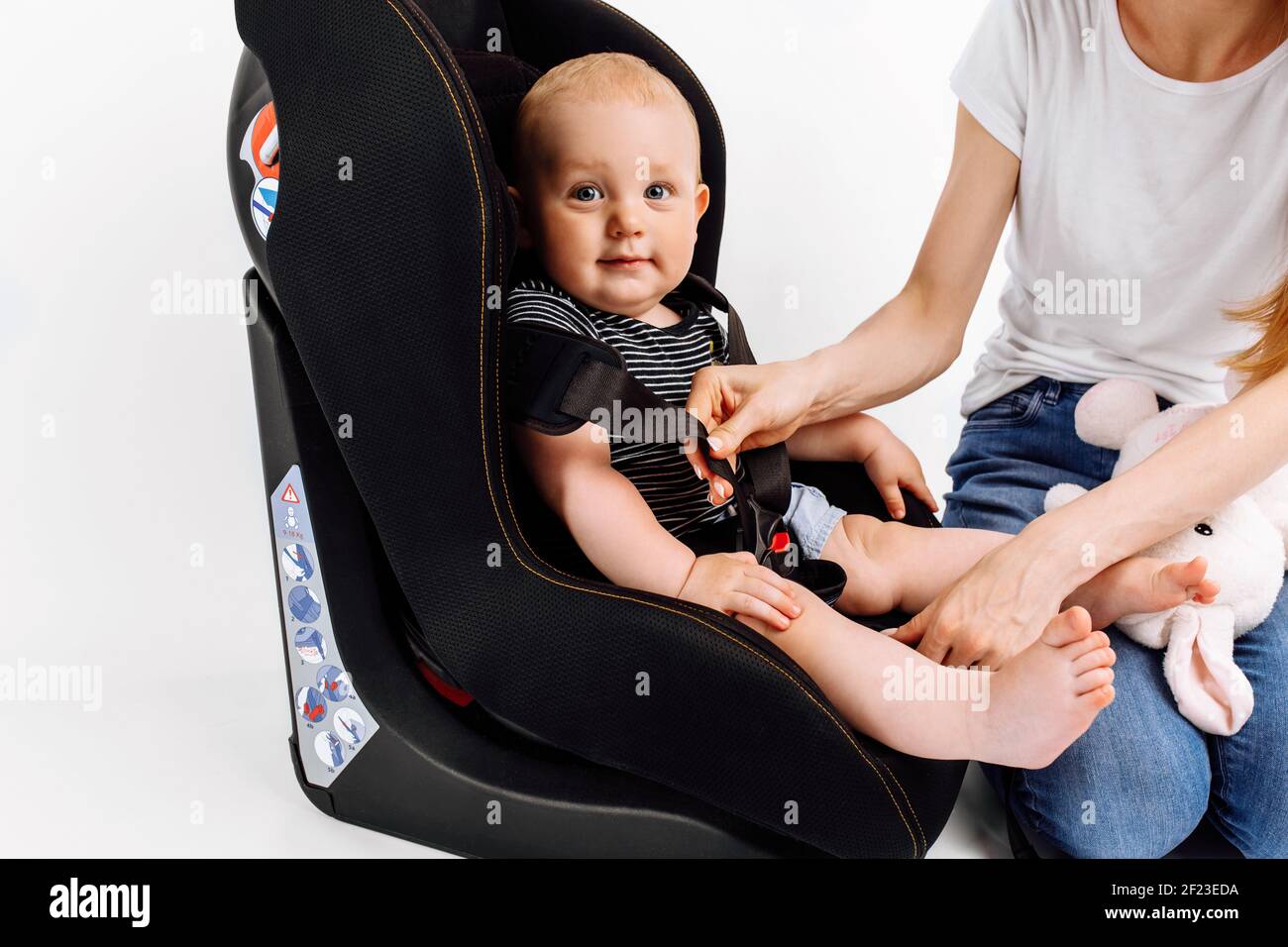 Mom straps her little baby in the car seat, baby in the car seat, on an ...