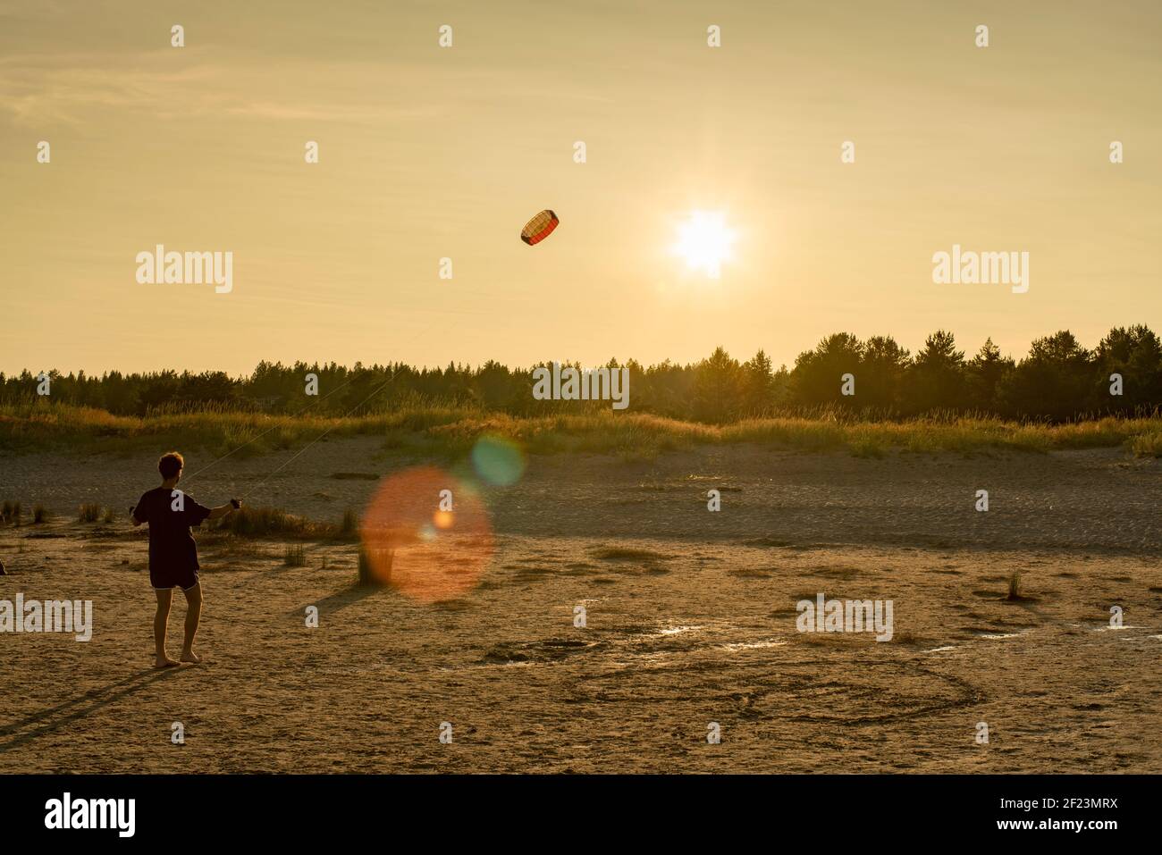 Man doing activities on the beach with abstract sun flare and sunset ...