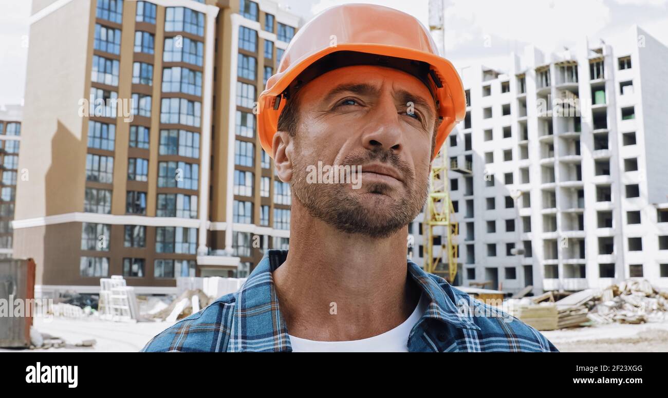 Handsome builder looking away on construction site Stock Photo - Alamy