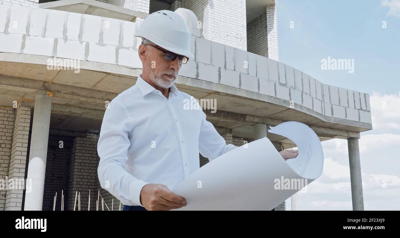 mature engineer with blueprint on construction site Stock Photo - Alamy