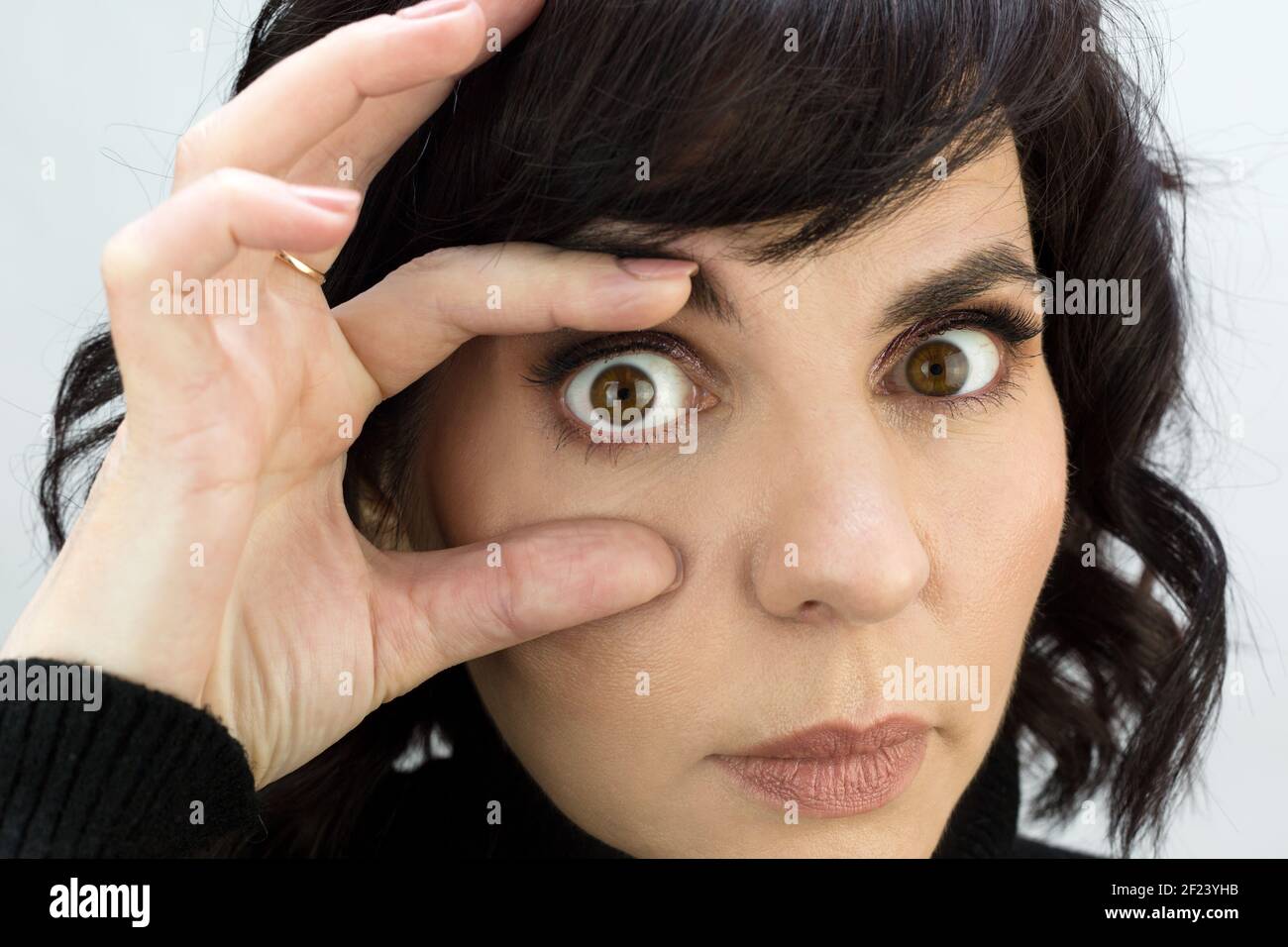The woman opened her eye wide with her fingers Stock Photo - Alamy
