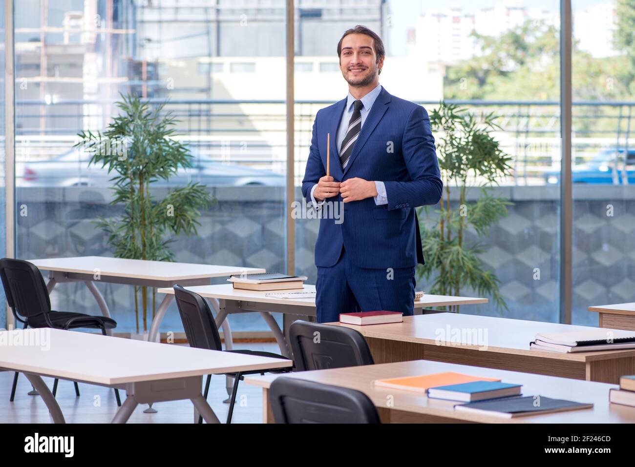 Young male teacher in suit in the classroom Stock Photo - Alamy