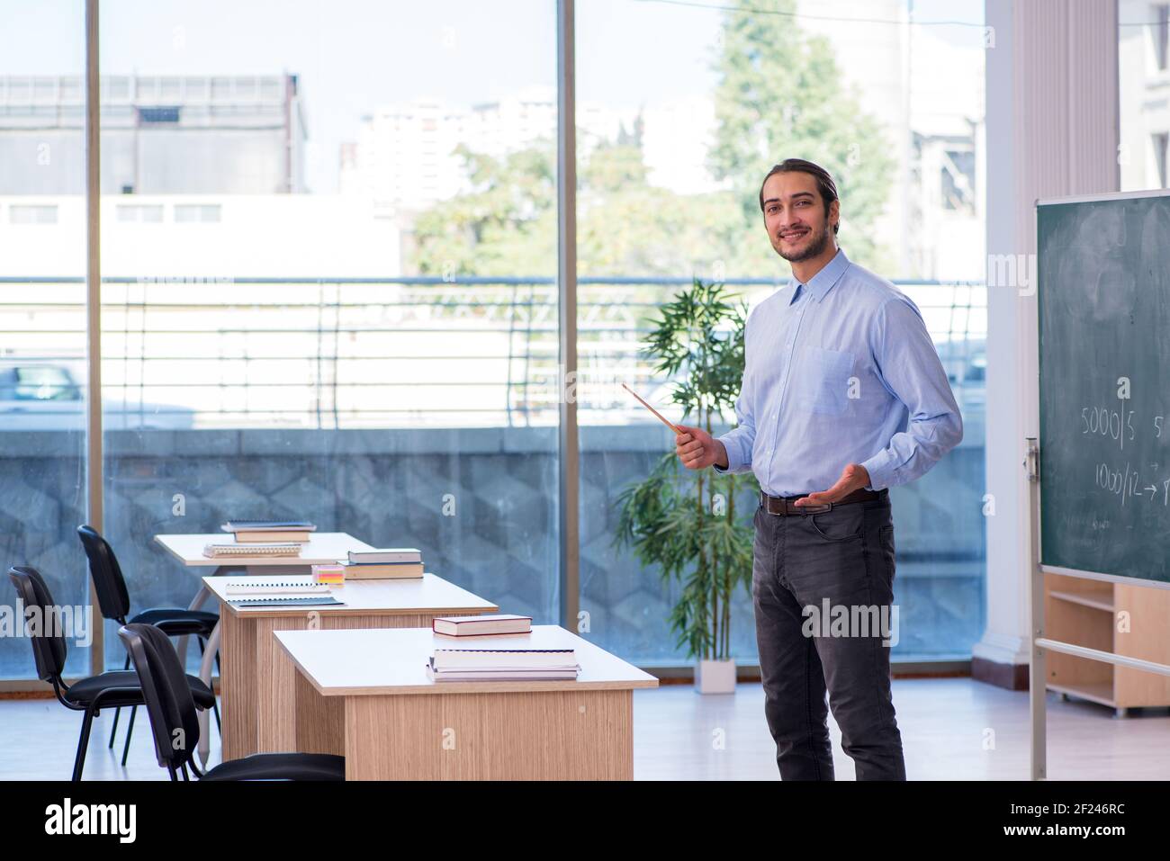 Young male teacher in the classroom Stock Photo - Alamy